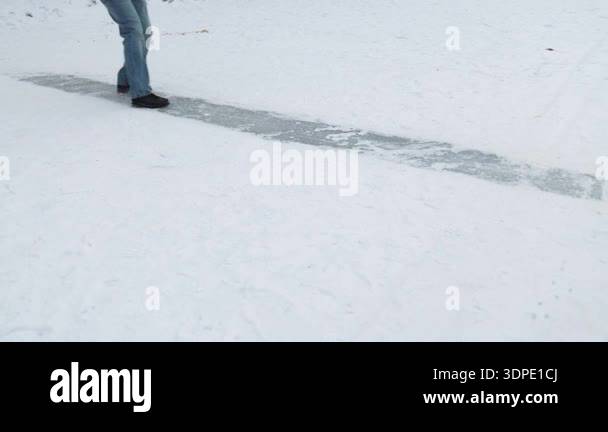 A young guy sliding the slippery street. Funny man feel himself a child ...