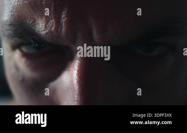 Extreme close-up cinematic portrait of an angry man frowning with ...