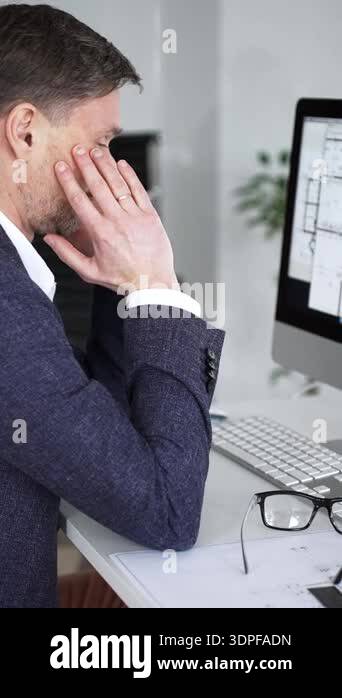 Overwhelmed male architect suffering from headache and eye strain while ...