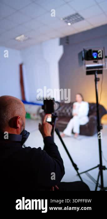 Rear view of a male photographer sitting in front of camera tapping by ...
