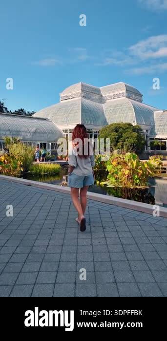 Long-haired woman walks by the tiled road along the pond with water ...