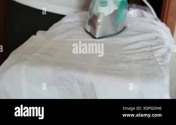 Female hand holding electric iron ironing clothes on ironing board ...