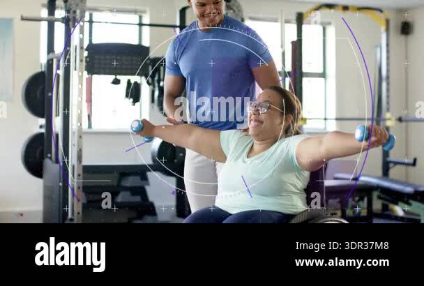 Woman in wheelchair receiving gym trainer cue, raising dumbbells to ...