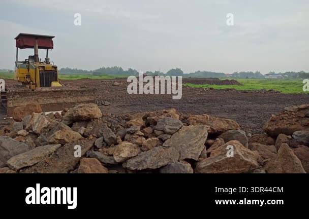 A bulldozer operates on a construction site to move soil and level the ...