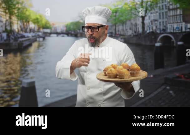 Man in chef uniform coughs into fist while holding a wooden tray of ...