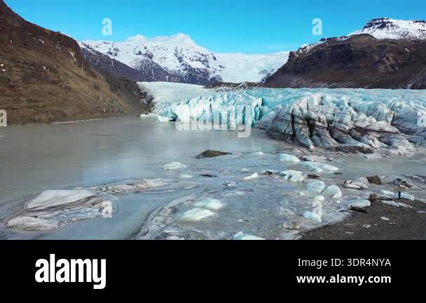 Large ice flows move at the base of a glacier in Iceland. Bright ...