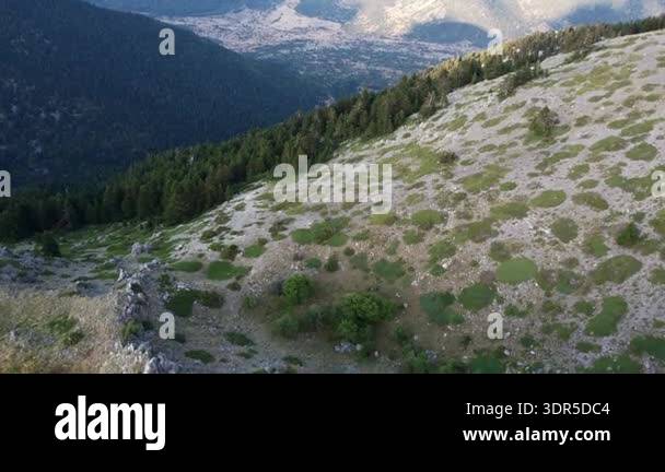 A sharp mountainside shows rough stone and sparse shrubs beside thick ...