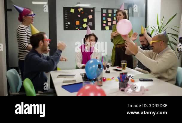 Team members gather in an office to celebrate a milestone. They enjoy ...