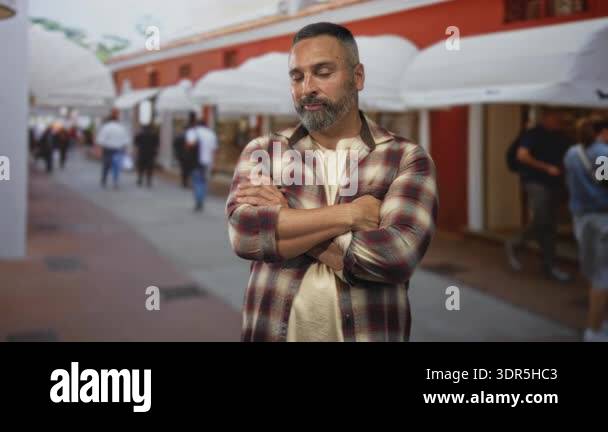 Man with crossed arms showing forearms on street lined with awnings and ...