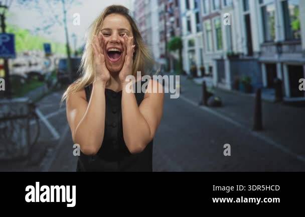 Young blonde woman cupping hand to mouth shouting on a narrow city ...