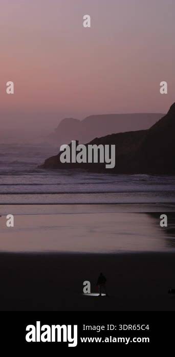 Soft sunset light over ocean waves and dark coastal cliff. Vertical ...