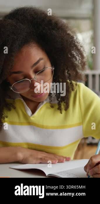 Concentrated African American student girl writing homework puzzled ...