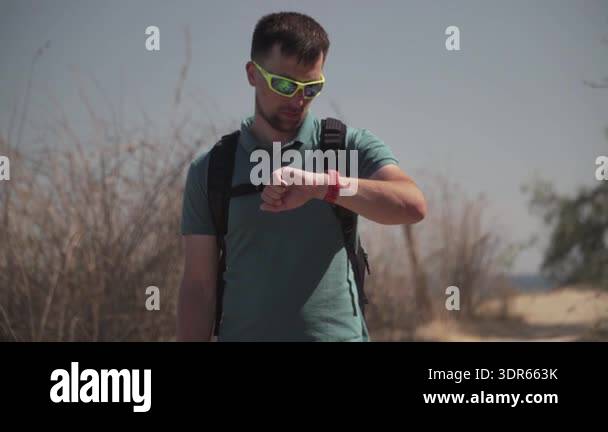 Tourist man in sunglasses checking sports watch with navigation and map ...