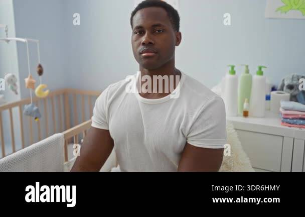 Young man sitting in a bedroom with a baby cradle and mobiles ...