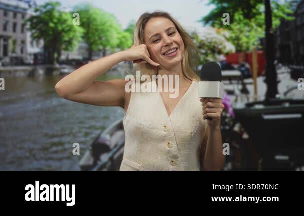 Young blonde reporter woman holding microphone and making phone hand ...