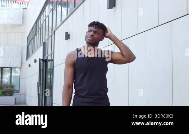 unsure African American man thinks and scratches his head on the street ...