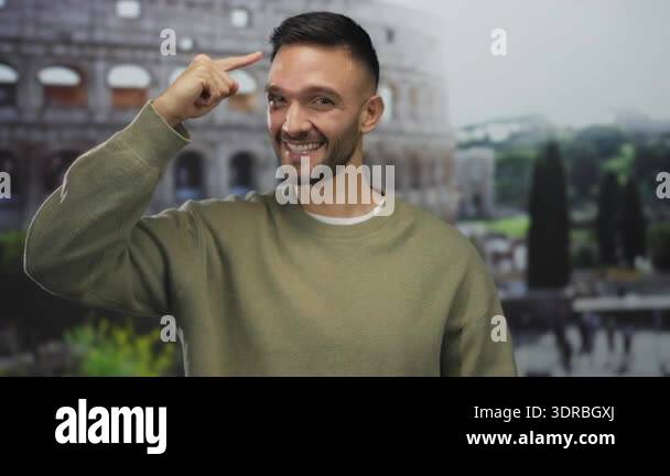 Hispanic man smiling and pointing at his head in front of rome's iconic ...