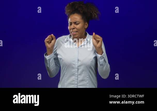 Woman grimacing and cringing with fists drawn close to chest and raised ...