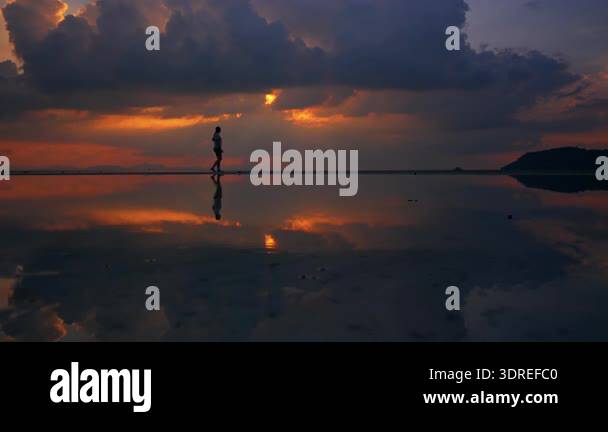 Distant Rear View of Woman Standing on Narrow Sandbank Surrounded by ...