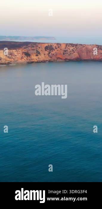 wide headland jutting into ocean under clear sky, smooth blue water ...