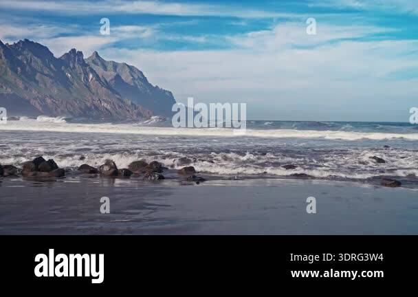 Atlantic Ocean waves crashing against dark volcanic rocks along rugged ...