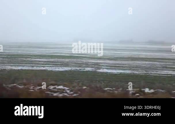 A desolate winter landscape showcases an agricultural field with sparse ...