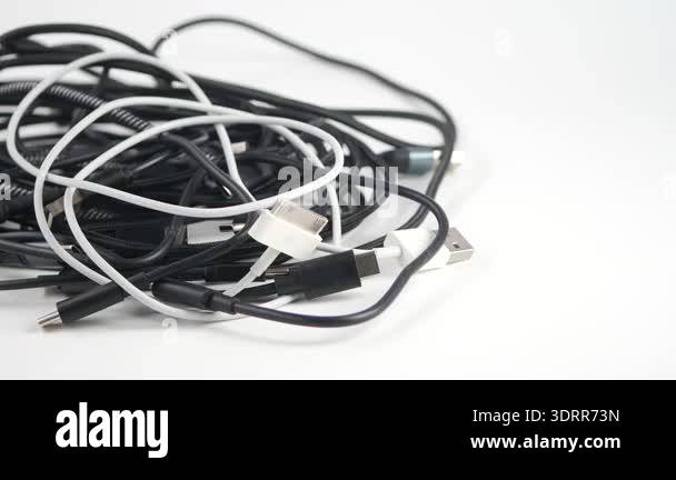 Several charging cables are tangled together on a plain background ...