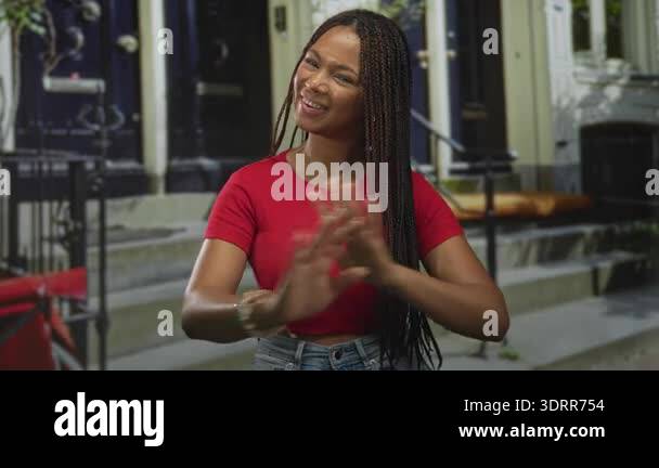 Woman in red crop top showing midriff with hands held up palms out at ...