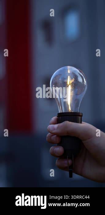A lamp without light in a hand against the background of a multi-story ...