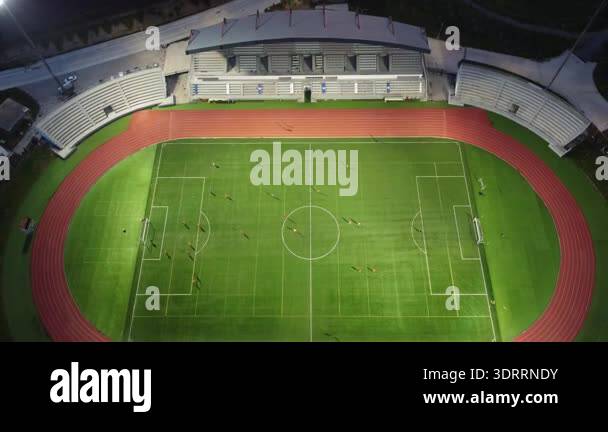 Cinematic top-down aerial footage of a green football pitch surrounded ...