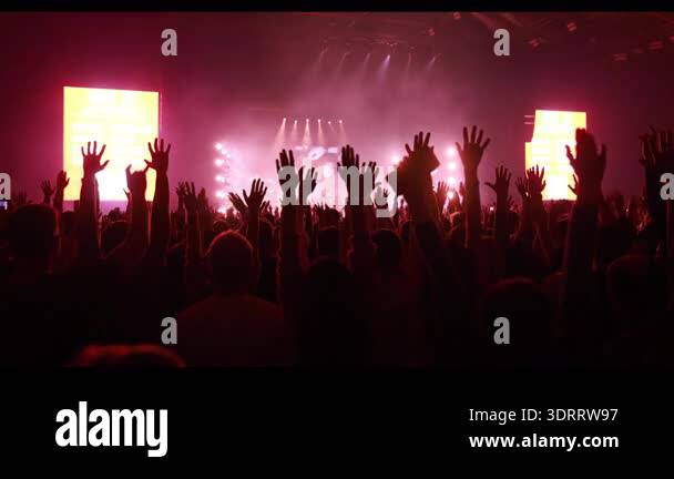 Close-up of a crowd waving hands at a live concert with bright stage ...