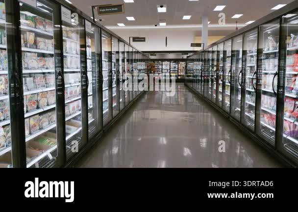 Long aisle of supermarket freezer section with glass-door refrigerators ...