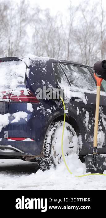 Electric vehicle charging its battery in cold winter weather with snow ...