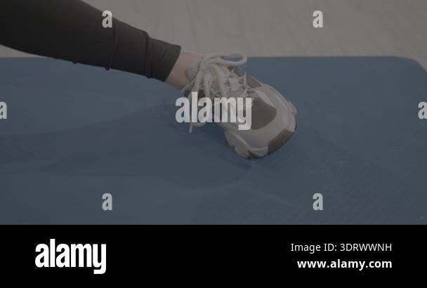 A young woman is doing a lateral lunge while standing on a blue mat in ...
