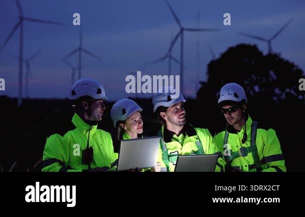 Engineers wearing safety helmets and jackets inspecting a wind turbine ...