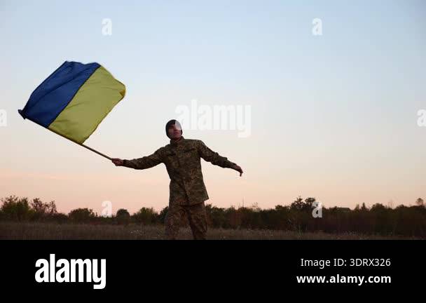Male military waving blue-yellow banner on liberated territory occupied ...