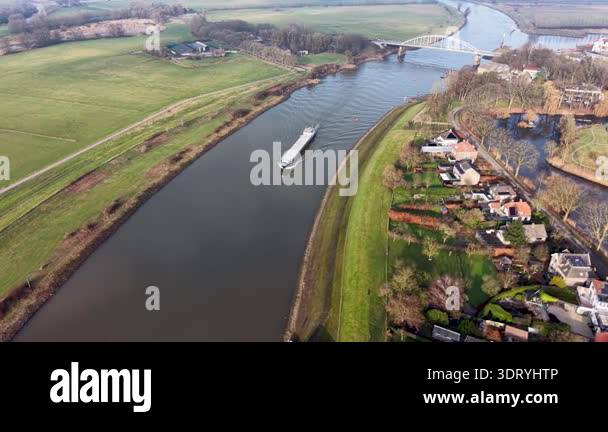 Aerial view of river bend with cargo vessel, docked boats, bridge, and ...