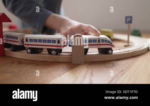 Child hands pushing white toy train around circular wooden railway ...