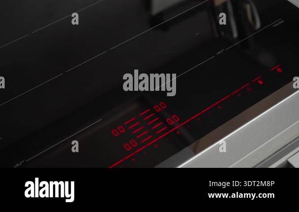 Black induction hob switches on with electronic beep sound. Red LED ...