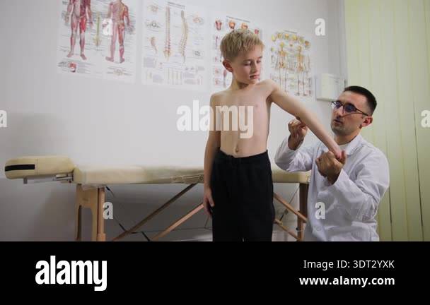 Male orthopedic doctor performing a physical examination of a young ...