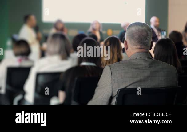 Back view of audience attending business conference with panel ...