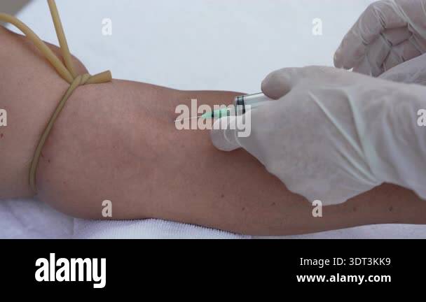 Close up of doctor or nurse taking a blood sample from arm vein with ...