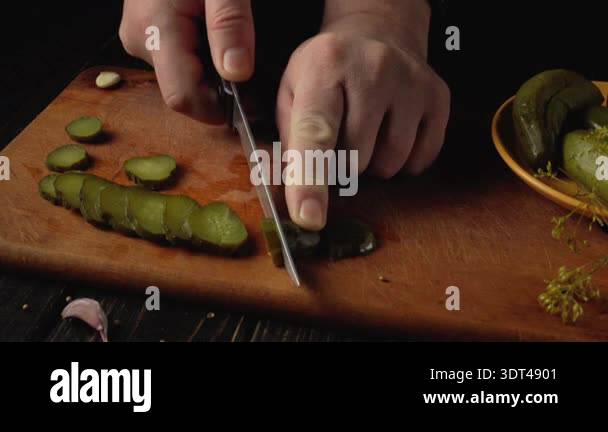 Hands skillfully slice pickles on a wooden cutting board, with a focus ...