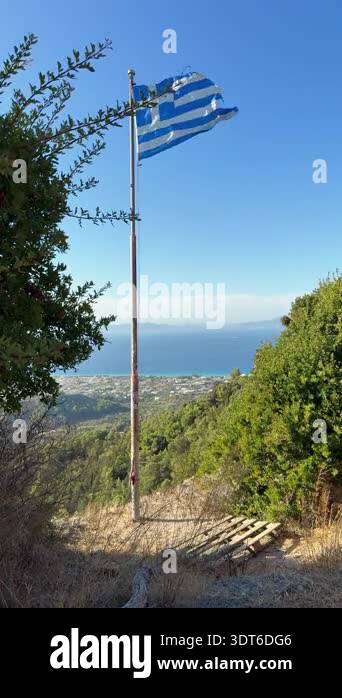 A vibrant Greek flag waves gracefully from a flagpole on a sunny ...
