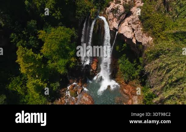 Aerial view flying up and away from a powerful waterfall cascading into ...