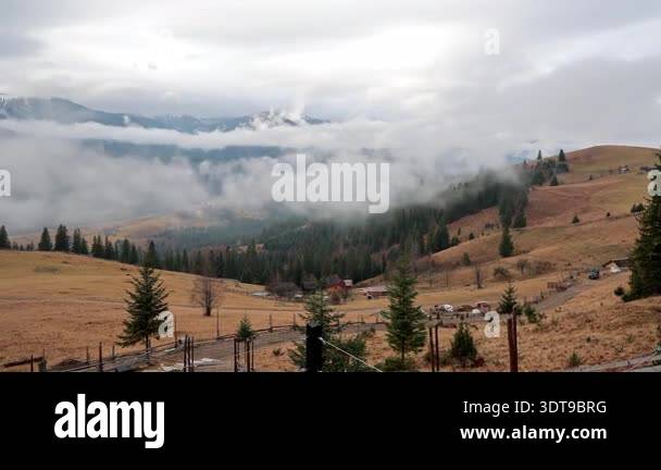 Majestic mountain valley landscape with low clouds and village houses ...