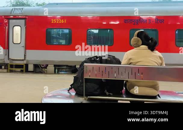 railway station platform scene with seated traveler watching train ...