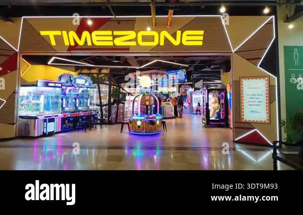 A large yellow neon Timezone logo sign illuminates the entrance of a ...
