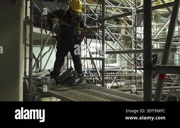 Worker securing construction materials at scaffolded job site Stock ...