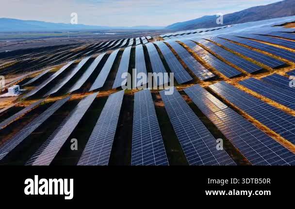 Rows of solar panels on sunlit hill slope. Photovoltaic installation on ...